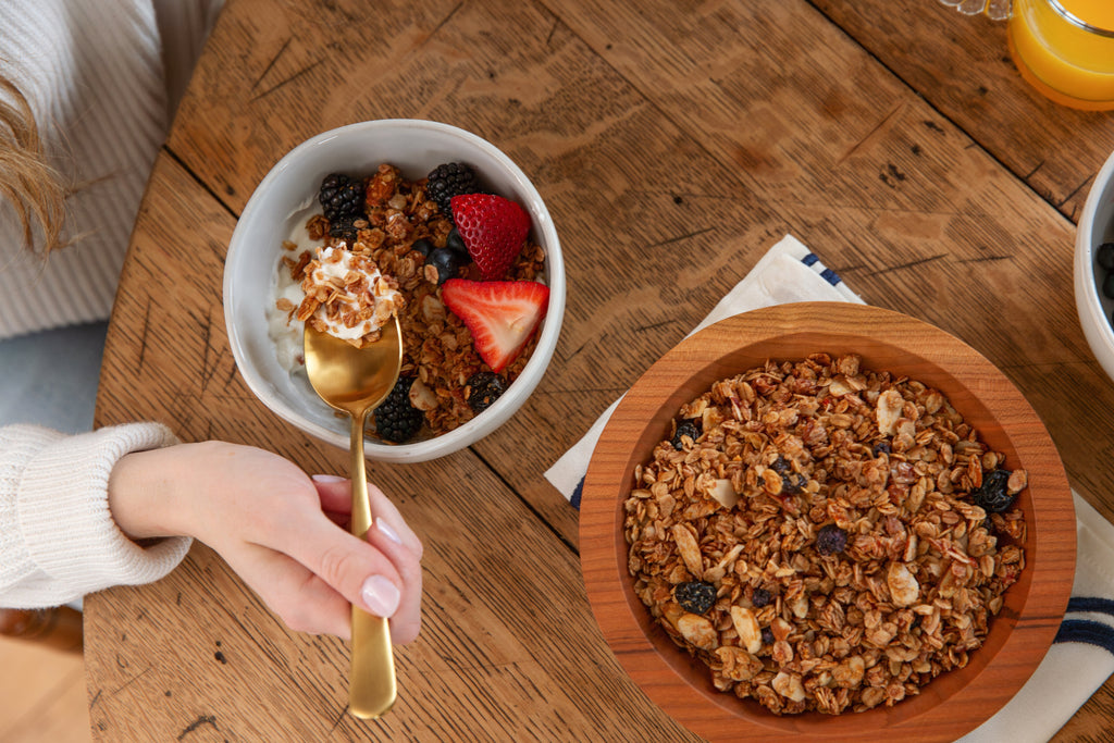 A bowl of yogurt topped with granola, strawberries, blackberries, and ...